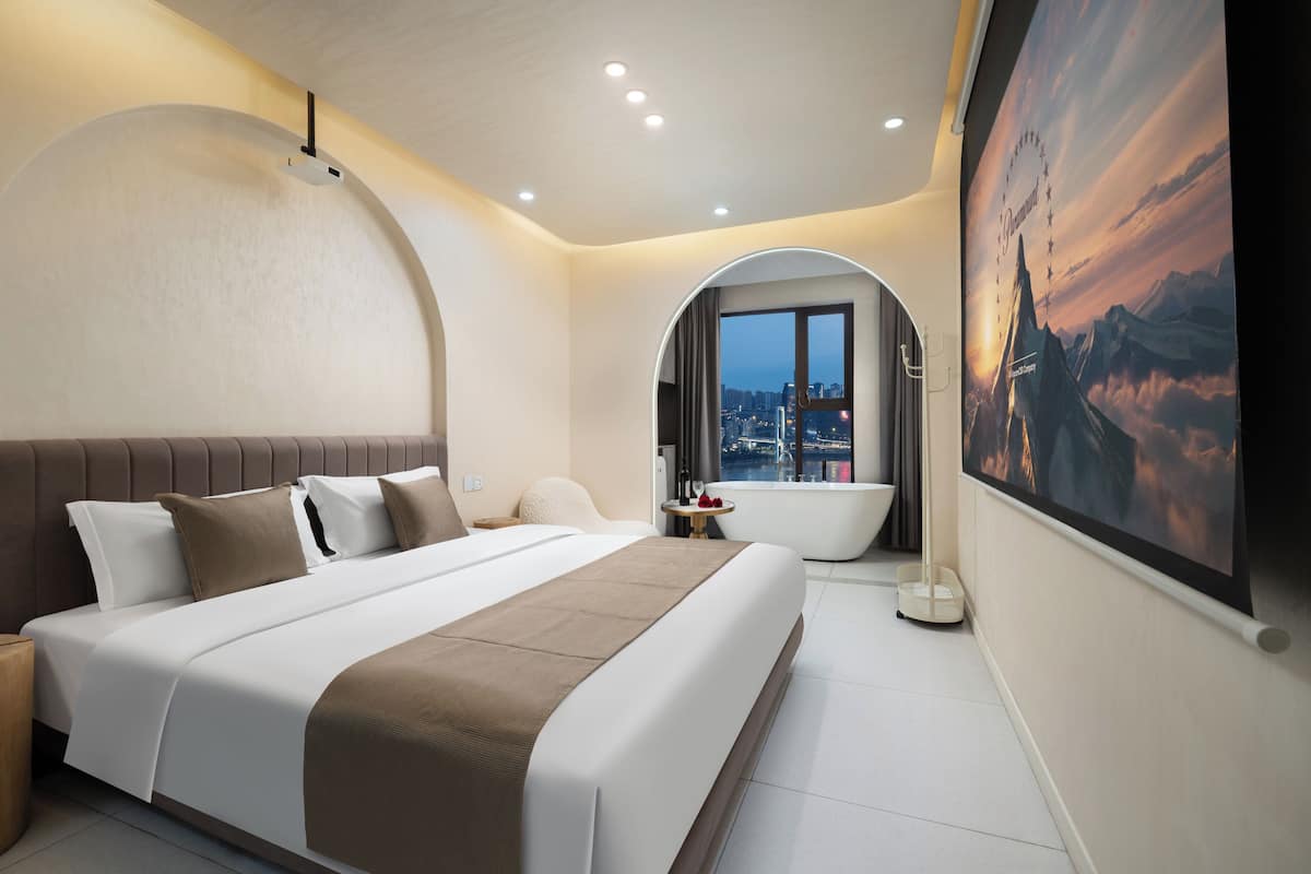Quarto de hotel moderno com uma cama grande, banheira e vista para a cidade.