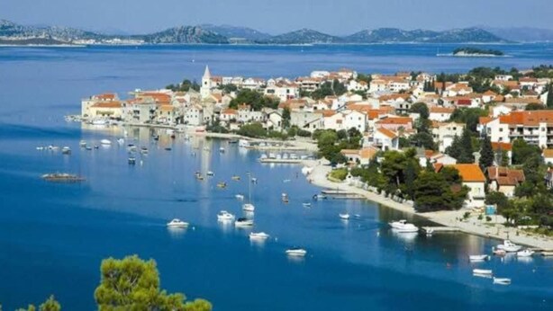 Uma vila costeira com edifícios, barcos e vista clara para o mar.
