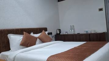 Quarto de hotel com cama, cabeceira de madeira, mesa de cabeceira e criado-mudo.