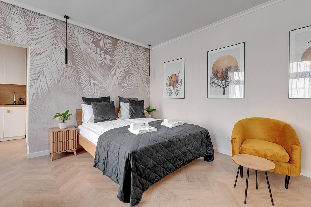 Quarto moderno com uma cama, mesa de cabeceira, cadeira e obras de arte na parede.
