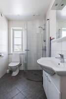 Uma casa de banho moderna com sanita, chuveiro e lavatório.