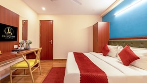 A hotel room with a bed, a desk, a chair, a television, and a ceiling fan.