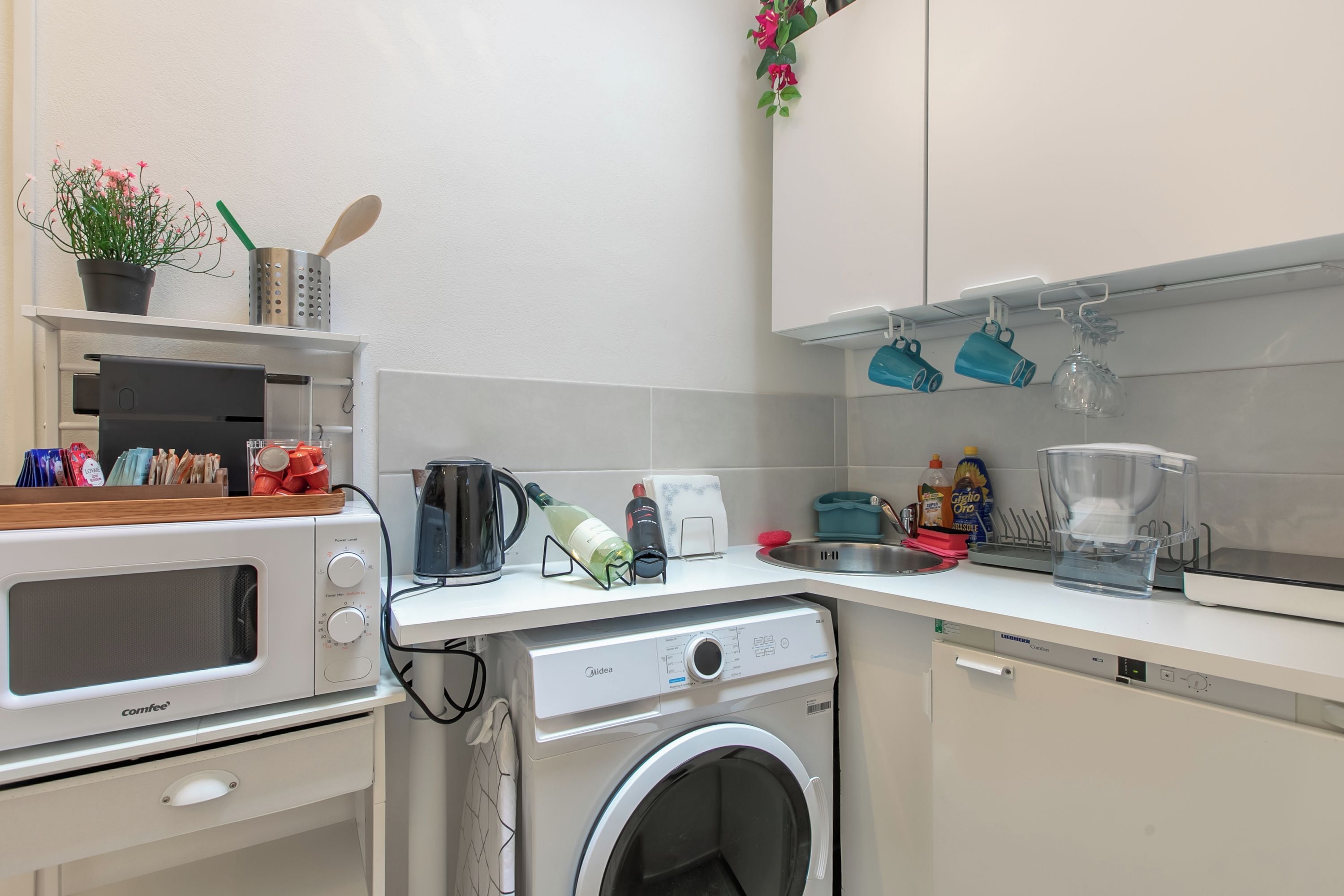 Uma cozinha compacta com micro-ondas, máquina de lavar e lava-louças.