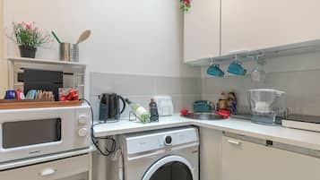 Uma cozinha compacta com micro-ondas, máquina de lavar e lava-louças.
