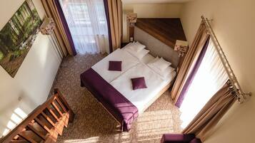 Quarto de hotel com uma cama, escada de madeira e vista para o exterior.