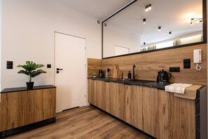 Uma cozinha moderna com bancada de madeira, pia, espelho e planta em vaso.