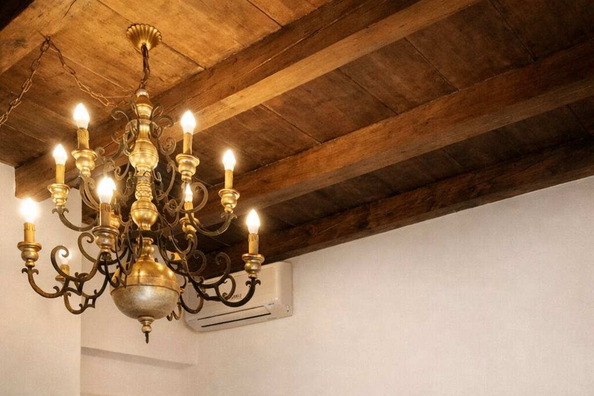Quarto com cama, mesa de cabeceira, abajur e lustre.
