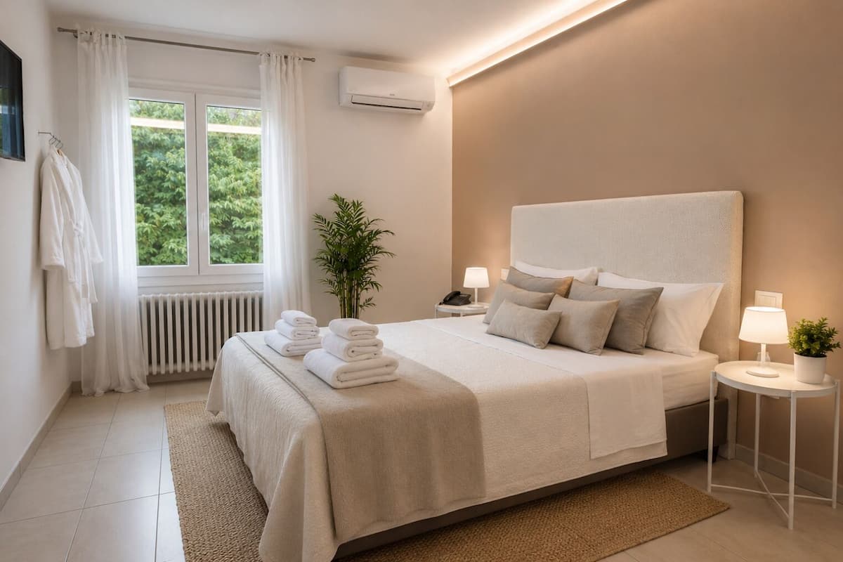 Quarto moderno com uma cama grande, mesas de cabeceira com luminárias, um radiador e uma janela com cortinas.