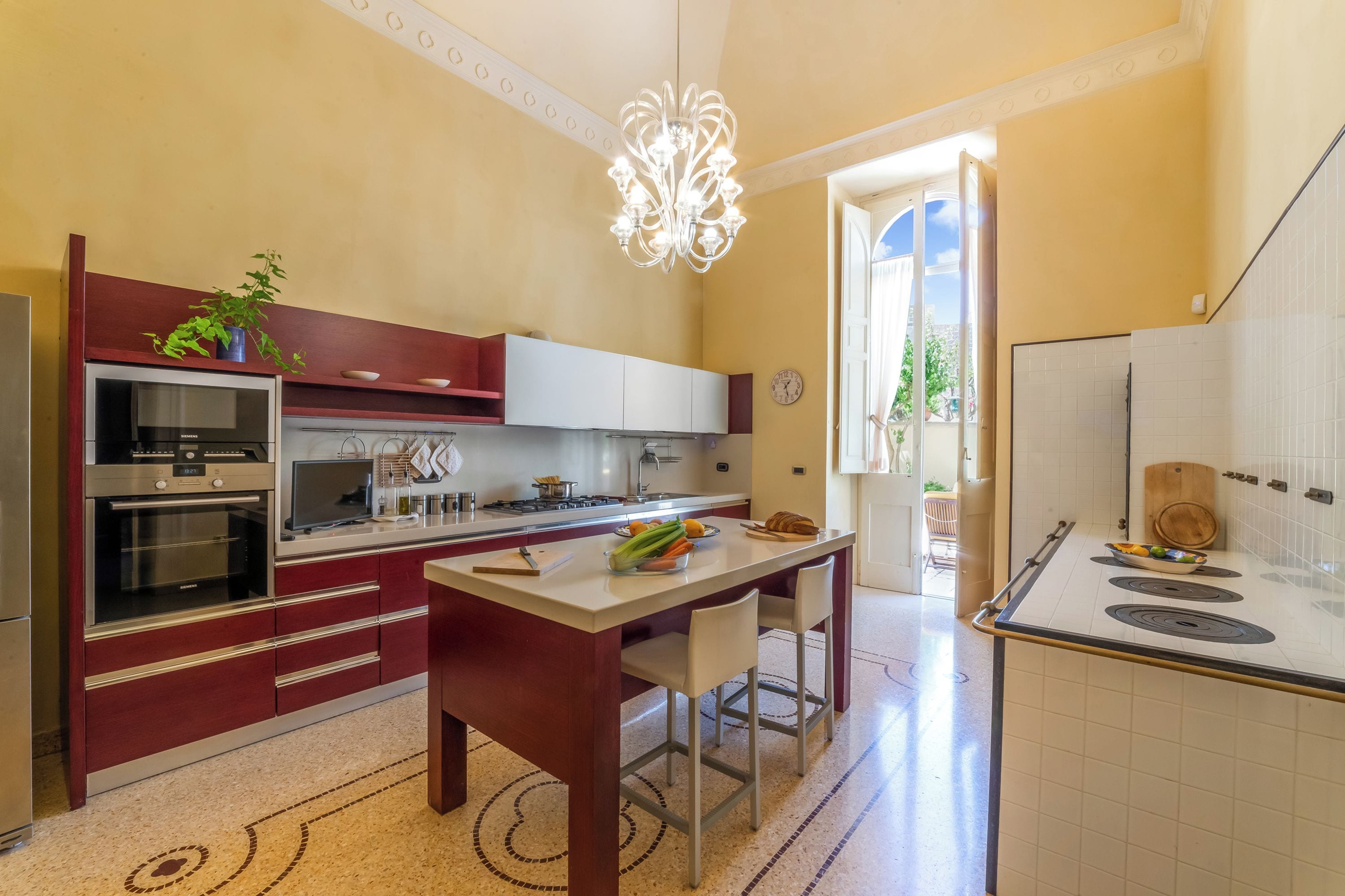Uma cozinha com ilha central, forno embutido e área de jantar com cadeiras.
