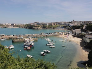 Uma vila costeira com um porto, praia de areia e edifícios ao fundo.