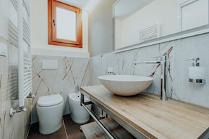 Uma casa de banho moderna com uma bacia grande, sanita e bidé.
