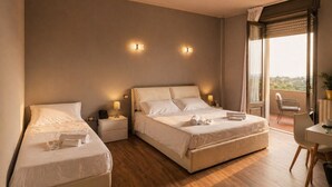 Quarto de hotel com duas camas, uma varanda com cadeira e mesa.