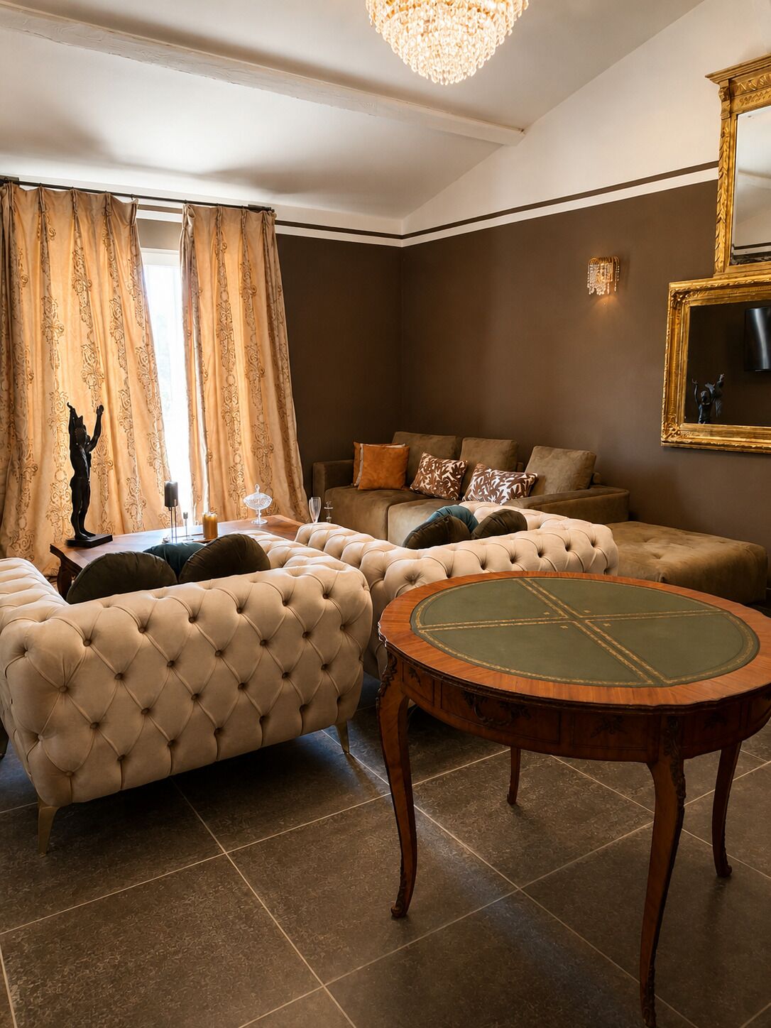 Uma sala de estar com um amplo sofá, uma mesa de centro redonda e um candelabro.