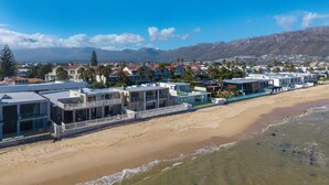 Um hotel à beira-mar, com vários edifícios, uma praia e montanhas ao fundo.
