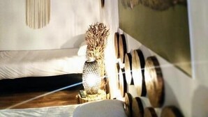 Quarto com cama, um sonho-pescador pendurado na parede, uma obra de arte emoldurada e um vaso decorativo.