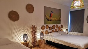 Quarto com duas camas, uma obra de arte pendurada na parede retratando um pássaro e um lustre.