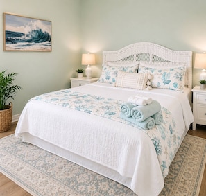 Quarto com cama, mesas de cabeceira, planta em vaso e um quadro na parede.