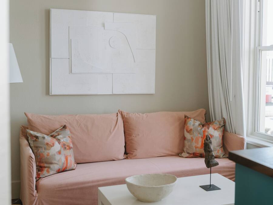 Sala de estar com sofá, mesa, uma tigela e uma obra de arte na parede.