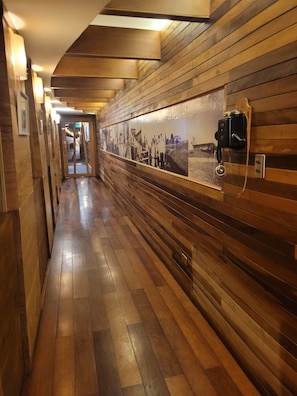 Um corredor com painéis de madeira, uma exposição de fotos na parede e um telefone de estilo antigo.