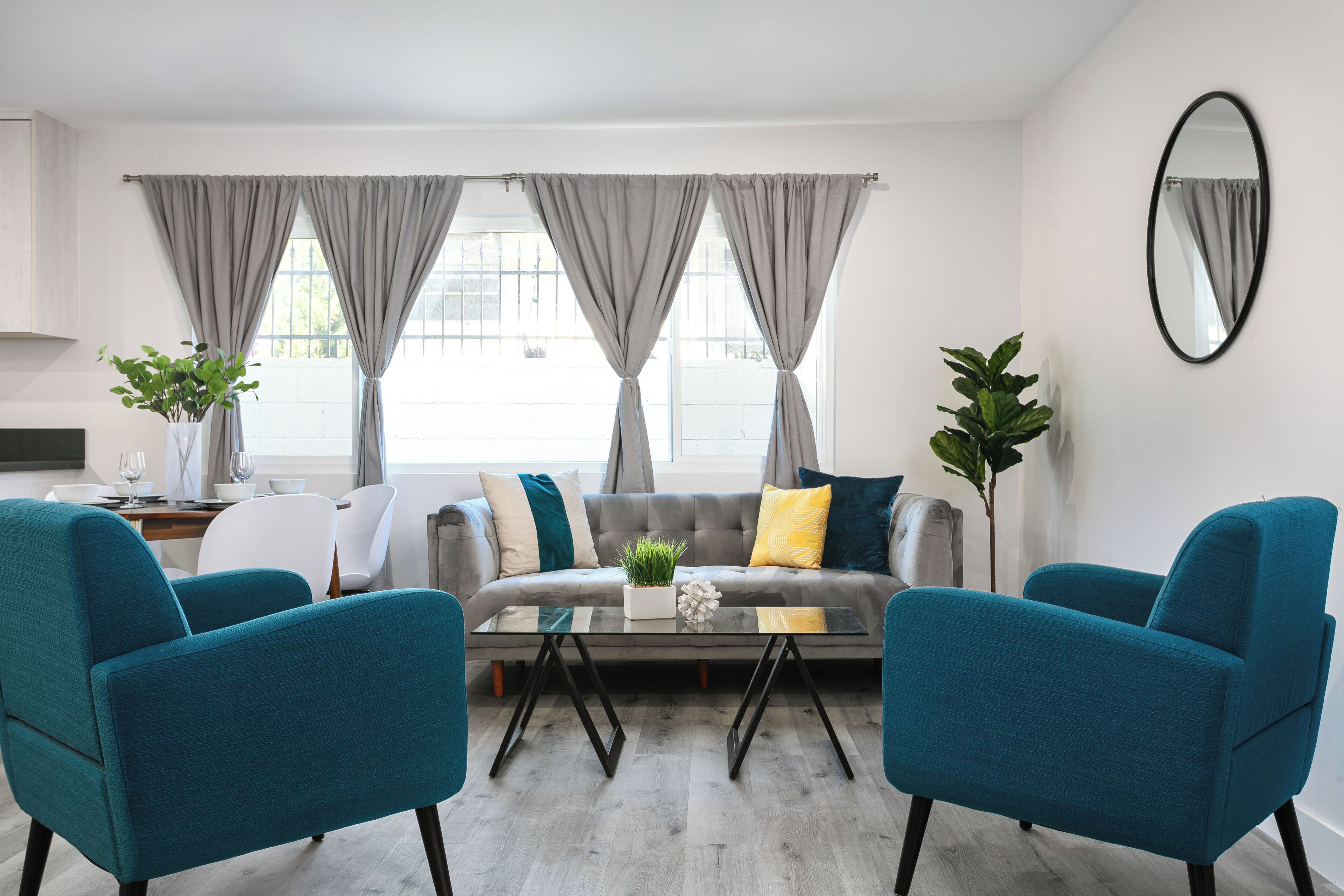 Uma sala de estar moderna com sofá, duas poltronas, mesa de centro e um espaço de jantar com mesa e cadeiras.