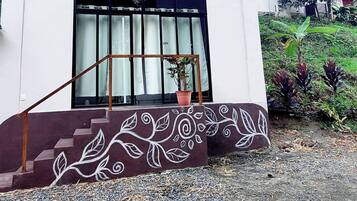 Um edifício moderno com telhado plano, uma janela grande e uma escadaria que leva a uma varanda.