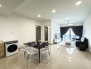 Uma sala moderna com área de jantar, máquina de lavar e uma janela grande com cortinas.