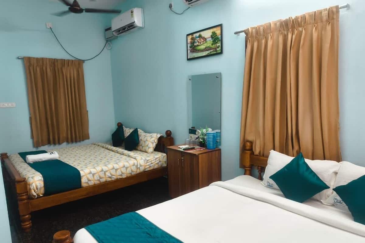 Quarto de hotel com duas camas, um guarda-roupa, um espelho e um aparelho de ar condicionado.