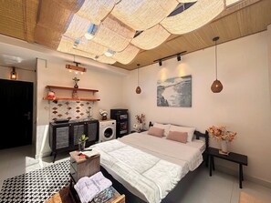 Quarto moderno com cama grande, máquina de lavar, frigorífico e teto com tecido pendente.