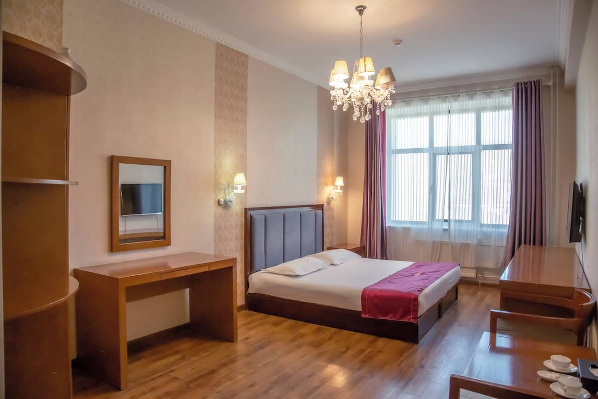 Quarto de hotel com cama, escrivaninha e um candelabro.