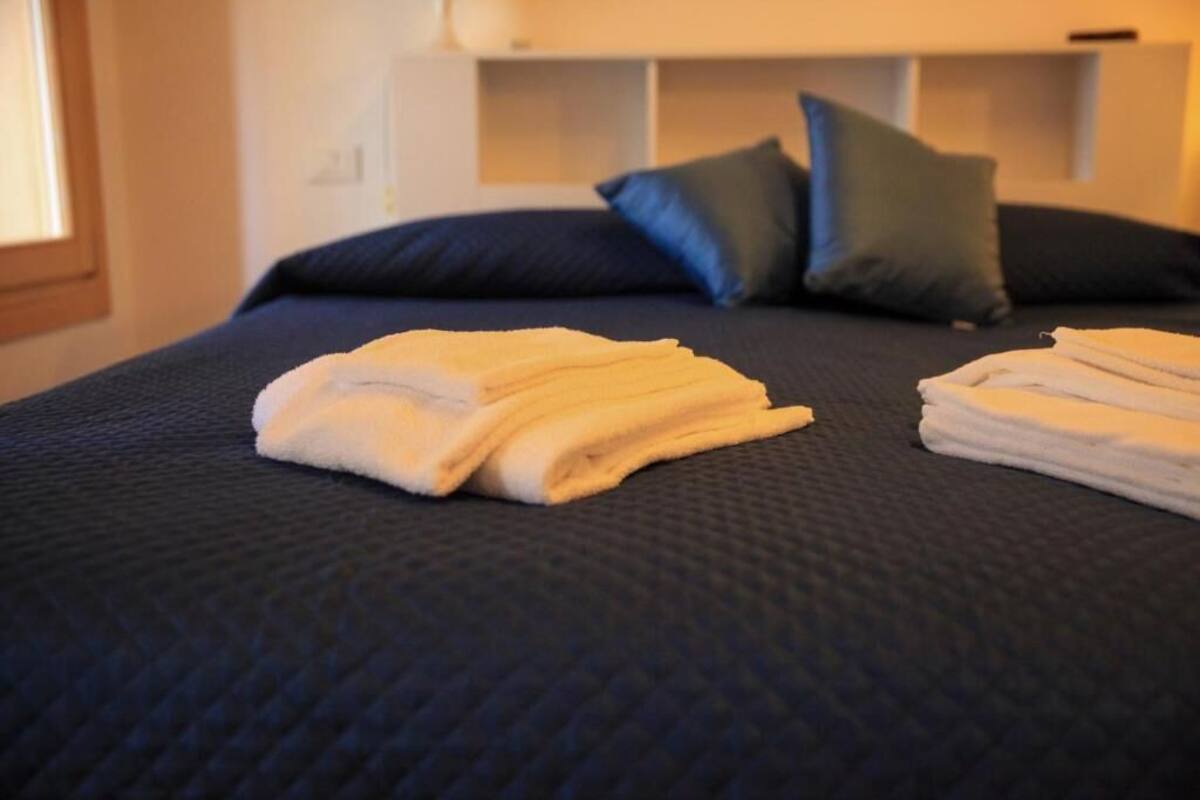 Cama bem arrumada com toalhas dobradas e almofadas.