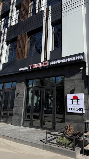 Um edifício moderno com uma placa indicando 'Hotel Tokyo' e um símbolo tradicional japonês.
