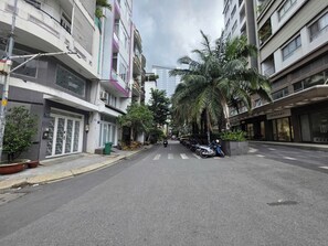 Uma rua com edifícios, motocicletas estacionadas e uma palmeira.