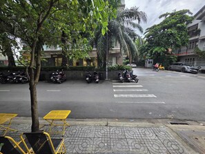 Vista da rua com motocicletas estacionadas, faixa de pedestres e edifícios ao fundo.