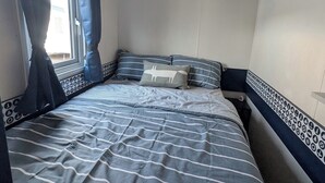 Quarto com cama, cortinas e janela.