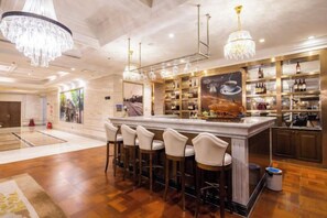 Uma área de bar com balcão, banquetas e um lustre.