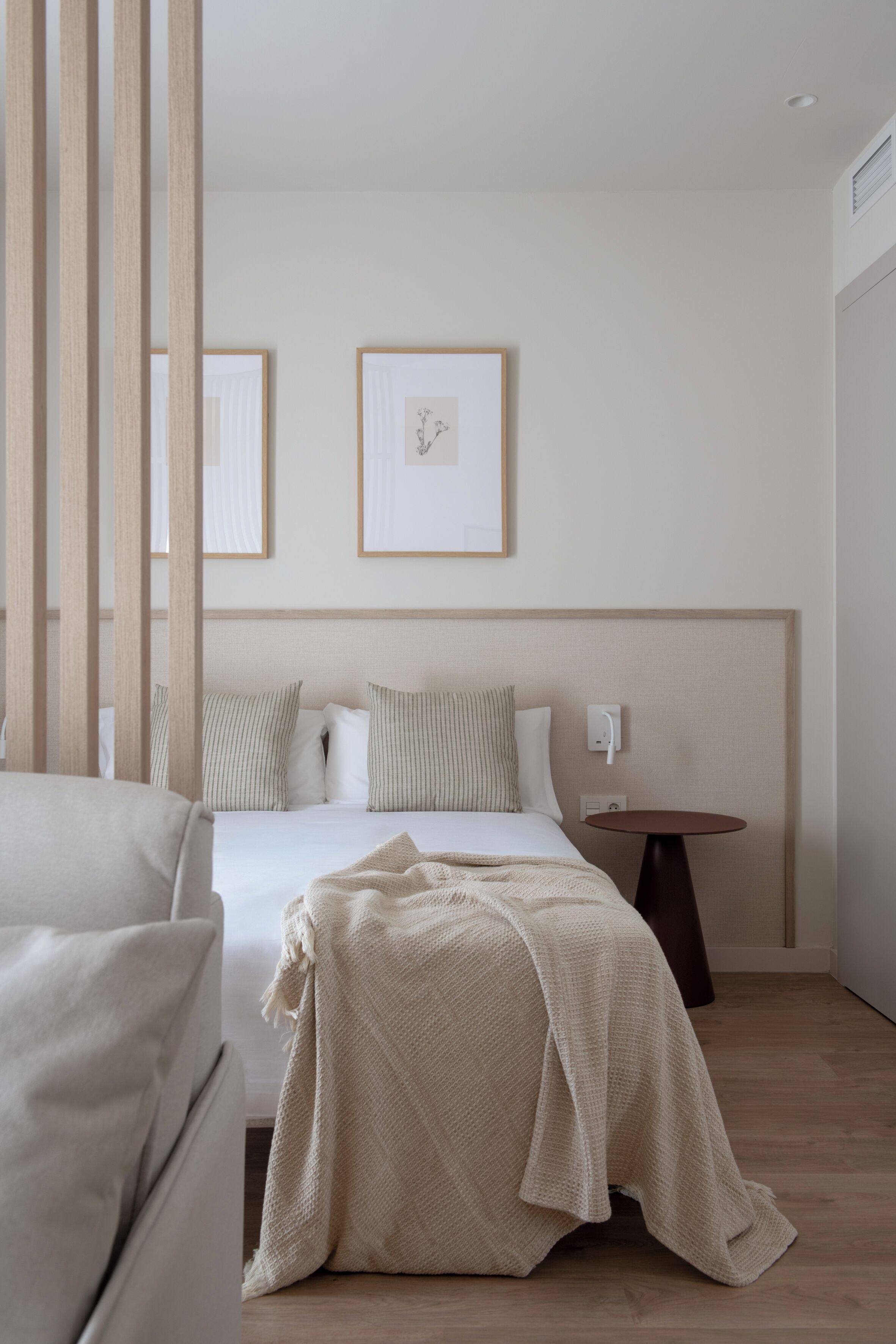 Quarto com cama, mesa de cabeceira e luminária na parede.