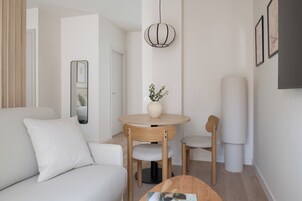 Uma sala de estar moderna com um sofá, uma mesa de madeira redonda e uma cadeira.