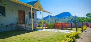 Um edifício com varanda coberta, escadaria e vista para uma montanha.