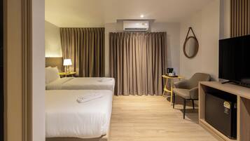 Quarto de hotel com duas camas, televisão, máquina de café e uma pequena mesa.