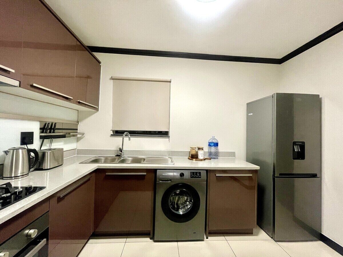 Uma cozinha compacta com máquina de lavar, geladeira, pia e fogão.