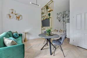 Uma sala de estar moderna com um sofá verde, uma mesa de jantar redonda e uma porta branca.