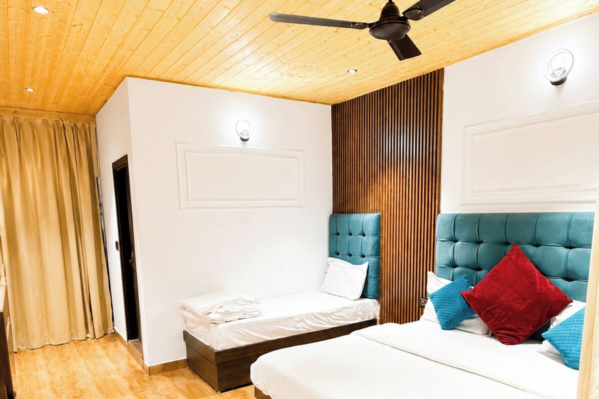 Quarto com duas camas, soalho de madeira, ventoinha no teto e painel de parede em madeira.