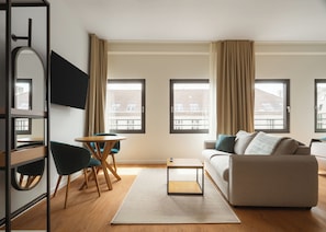 Uma sala de estar moderna com um sofá, uma mesinha, uma cadeira e uma TV fixada na parede.