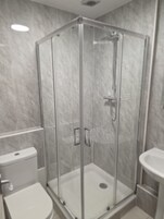 Uma casa de banho moderna com cabine de duche em vidro, sanita e lavatório.