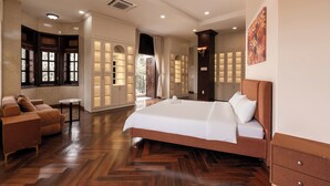 Quarto de hotel com uma cama grande, um sofá, uma mesa pequena e vista para o exterior.
