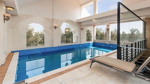 Piscina com guarda-corpo de vidro, um banco e escadaria com guarda-corpo de vidro.