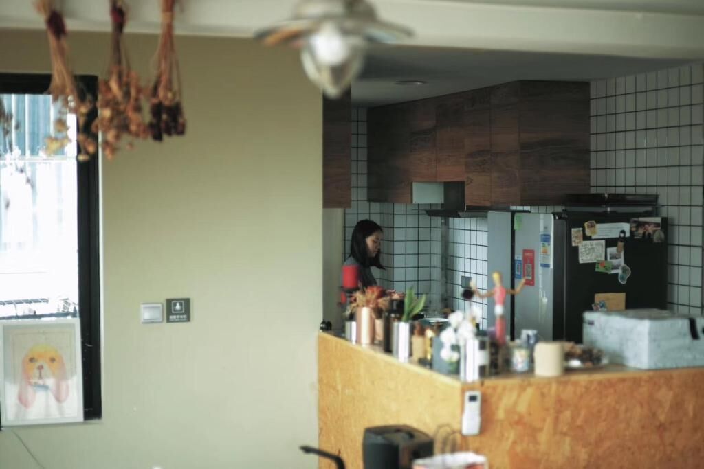 Cozinha com uma pessoa em frente ao balcão, um ventilador de teto e um revestimento de azulejos.