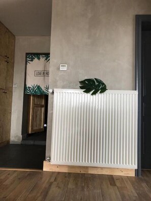 Quarto com radiador, piso de madeira e uma planta.