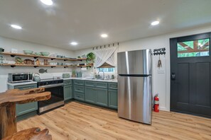 Uma cozinha moderna com armários verdes, eletrodomésticos de aço inoxidável e piso de madeira.