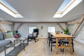 Quarto estilo loft com área de jantar, sofá e mesa de centro de vidro.